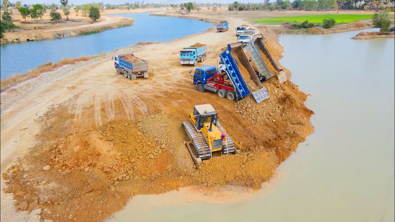 Amazing bulldozer and dump trucks filling soil into river to make road ...