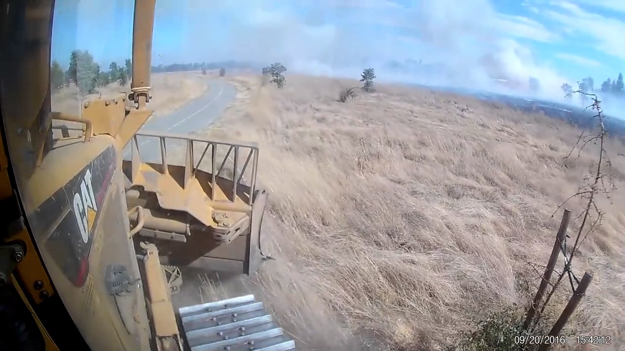 Fire dozer tracking down a highway, then turns into an active fire line ...