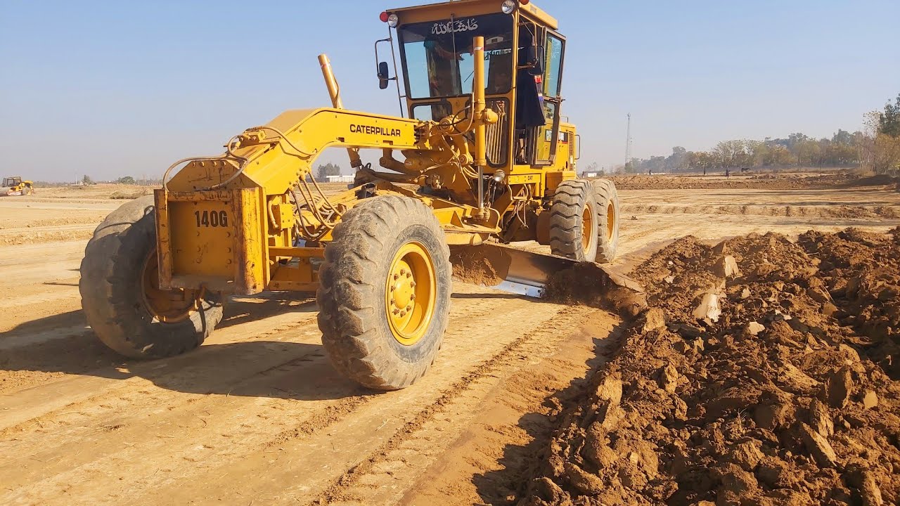 catterpiller 140 g grader operator is leveling the soil and making the ...