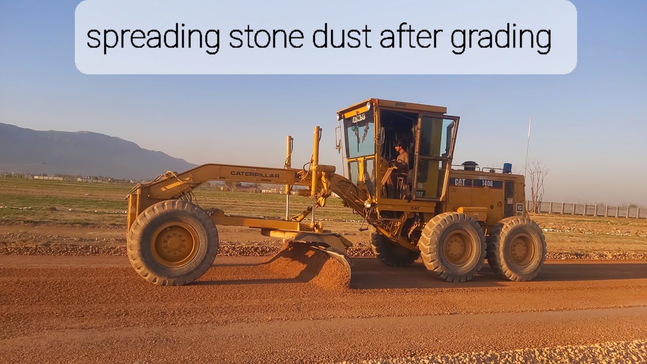 spreading stone dust after grading base course road construction with ...