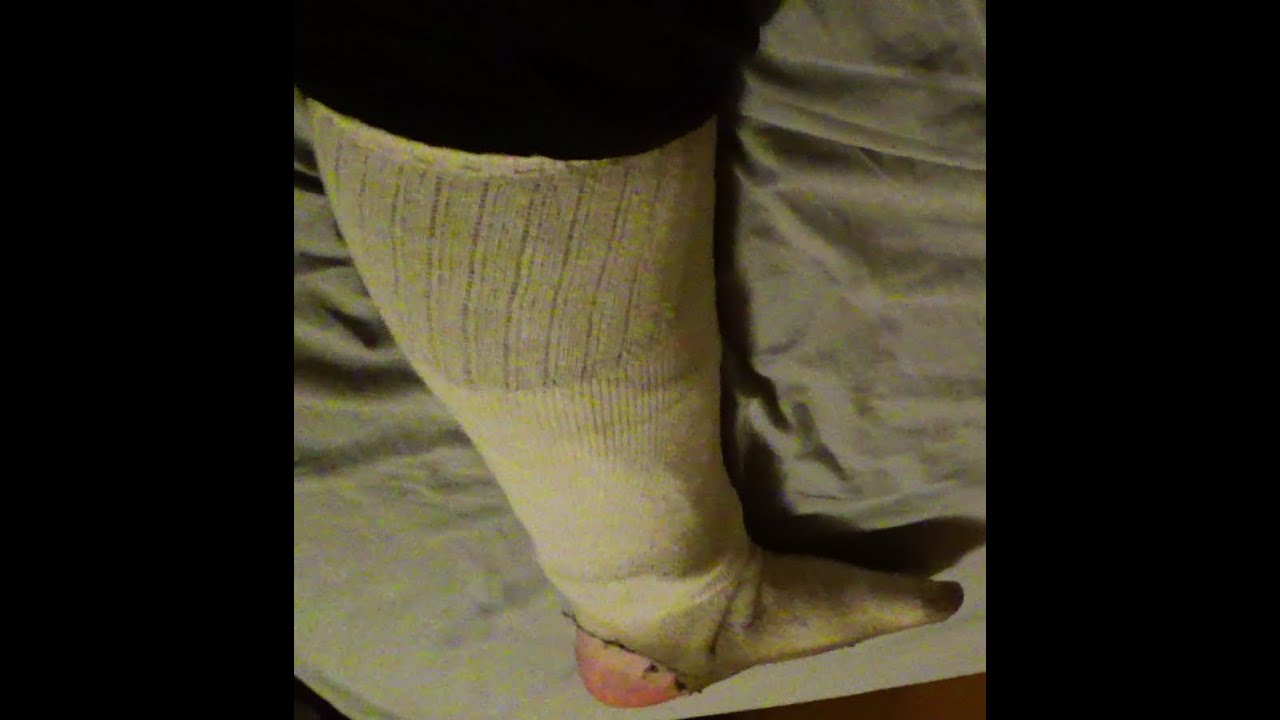 showing holey white tube socks in bed with sweatpants on and ...