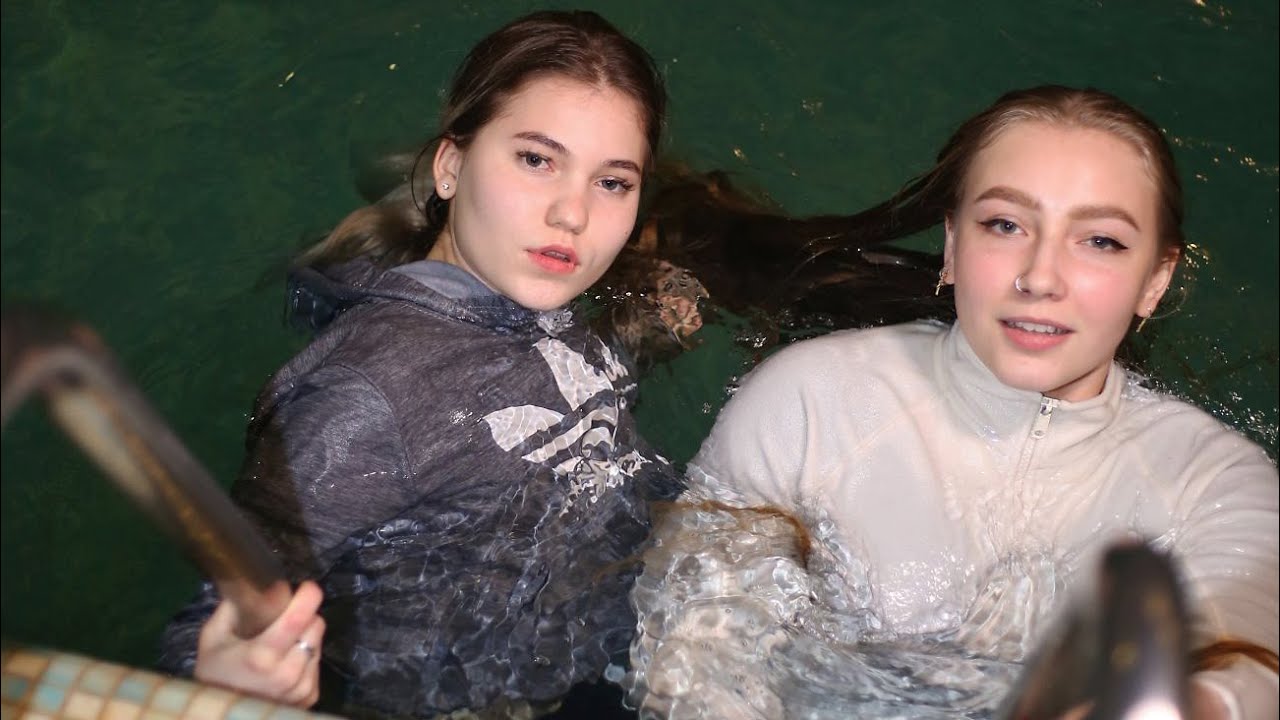 WET AND HAPPY - TWO FRIENDS PLAYFULLY SWIM IN THEIR CLOTHES IN THE POOL ...