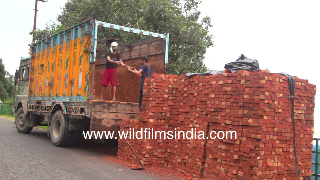 Bricks being offloaded from a truck and piled up alongside road - time ...