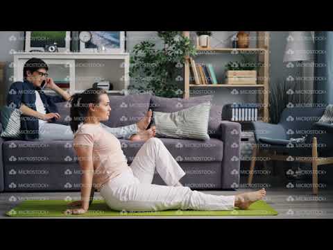 Housewife doing yoga when husband working with laptop talking on mobile phone
