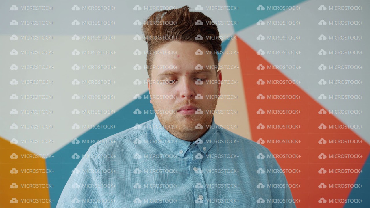 Portrait of sad young man looking at camera with sadness on colorful ...