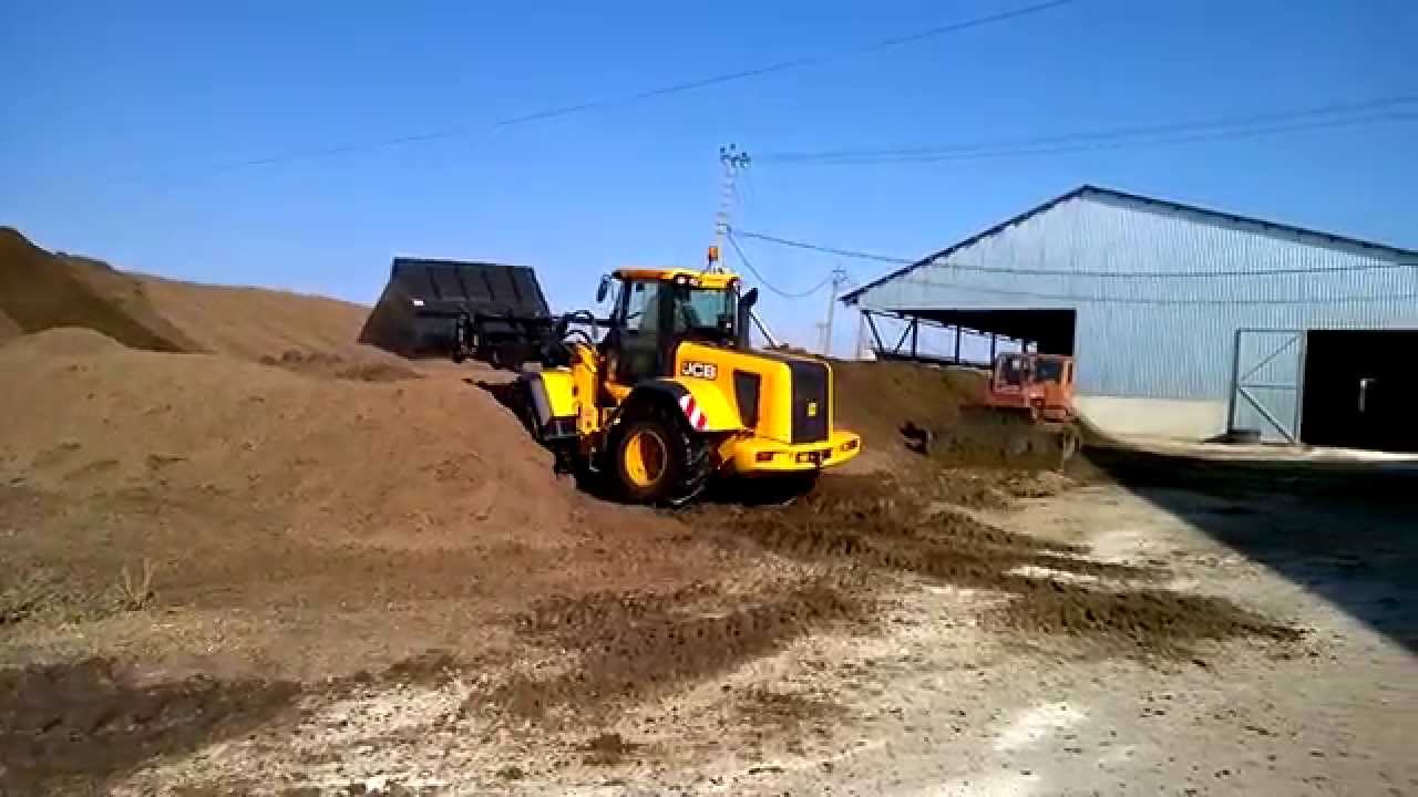 Фронтальный погрузчик JCB Farm Master 434S в работе на сыпучем навозе ...