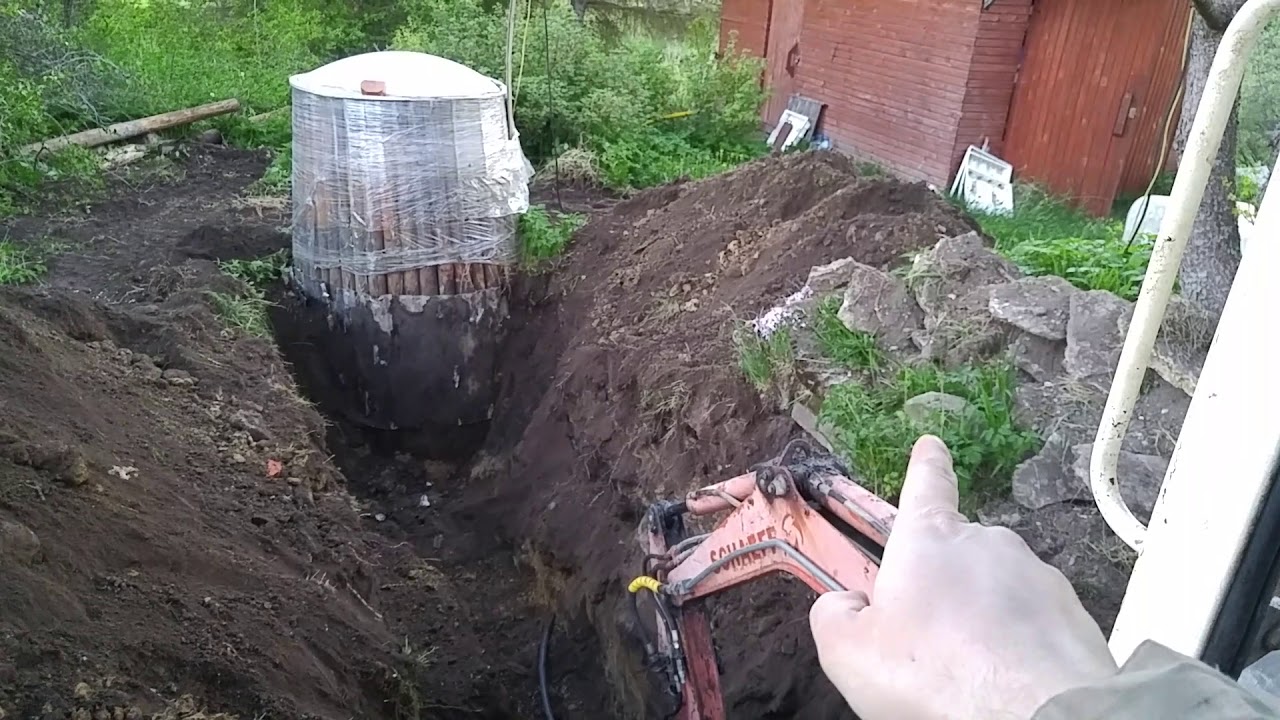 mini excavator digging a water mains ditch in rocky fill in northern EU ...