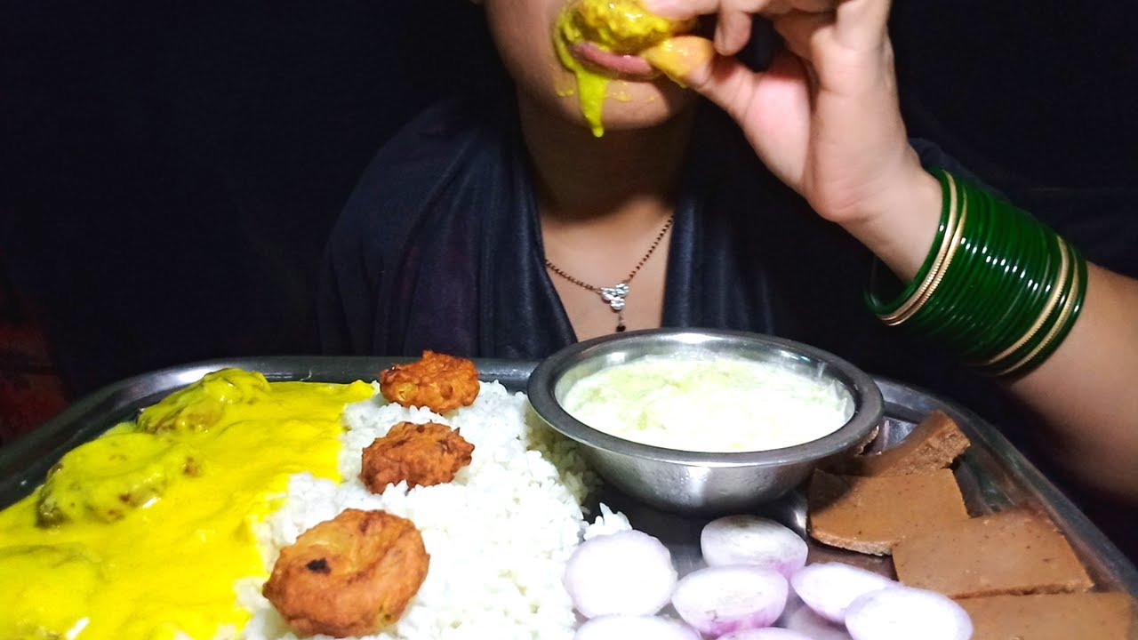 eating indian food pakoda kadhi, rice, bottle gourd rayta, and water ...