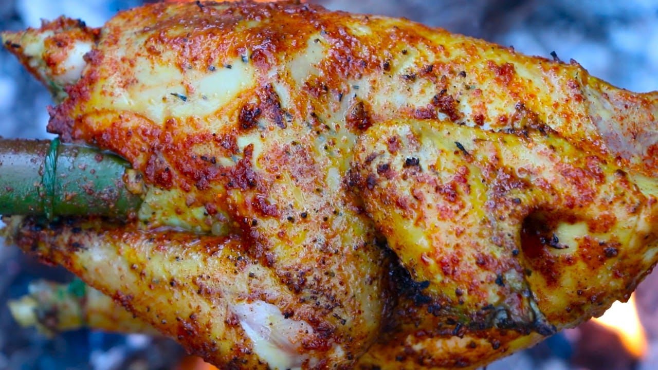 Hand-slaughtered rooster marinated and roasted by rolling over the open ...