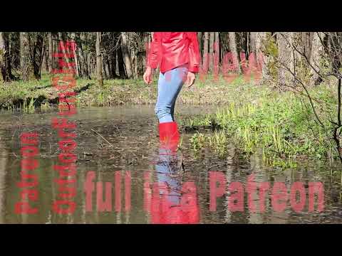 A girl in red rubber boots plays in a puddle