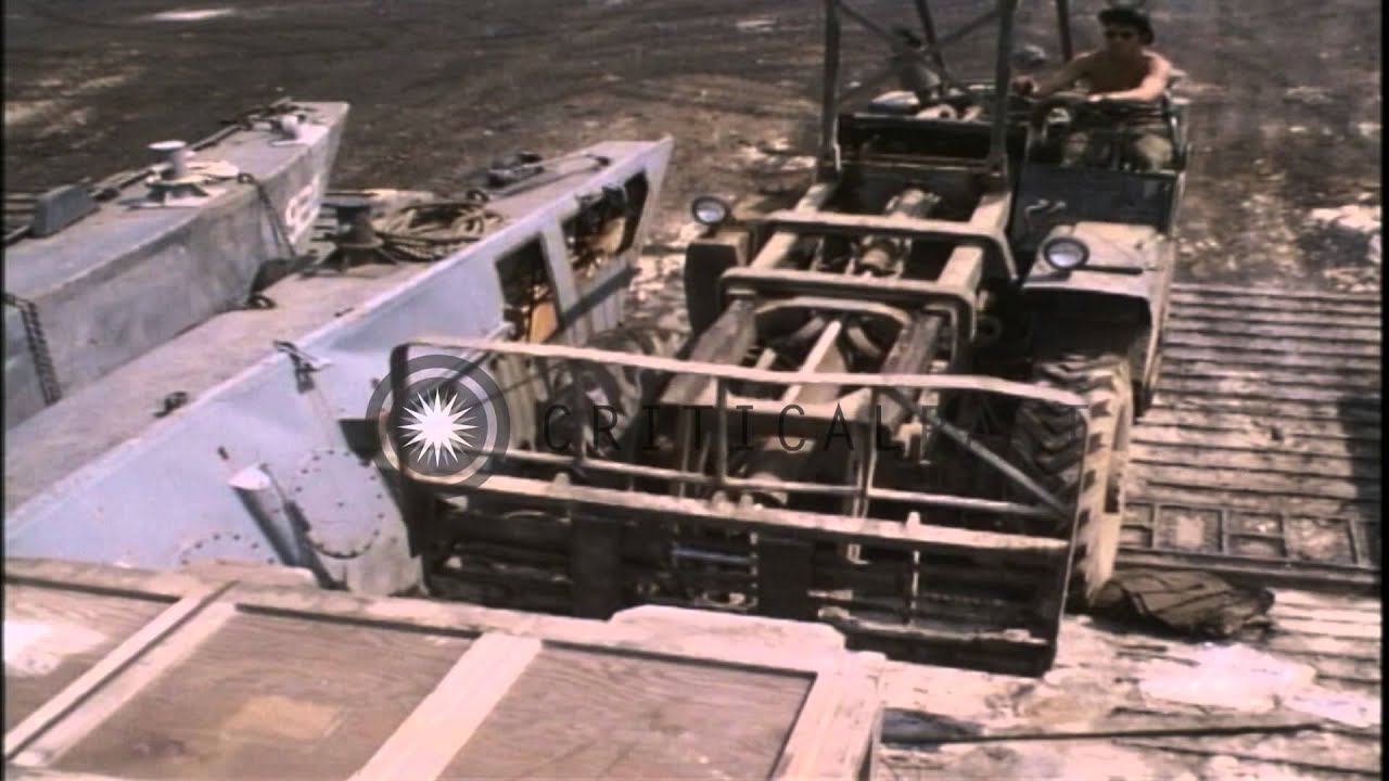 A fork lift unloads crates from US Navy landing craft LCM-8 at ramp and ...