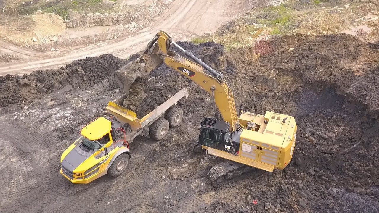 Экскаватор Cat 374F L грузит вскрышей самосвалы Volvo A40G - drone ...