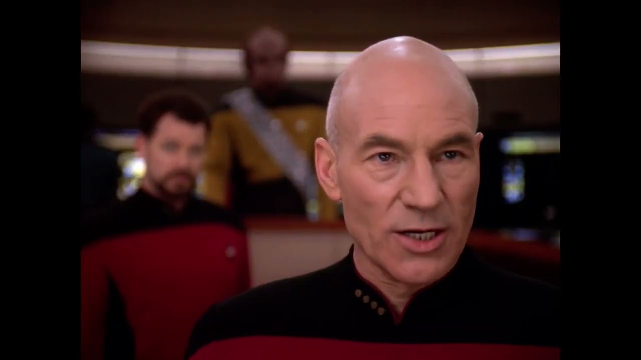 Captain Picard and Commander Tomalak stare at each other across the ...