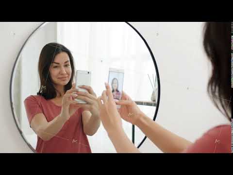 Slow motion of beautiful woman taking selfie in bathroom in front of mirror using smartphone