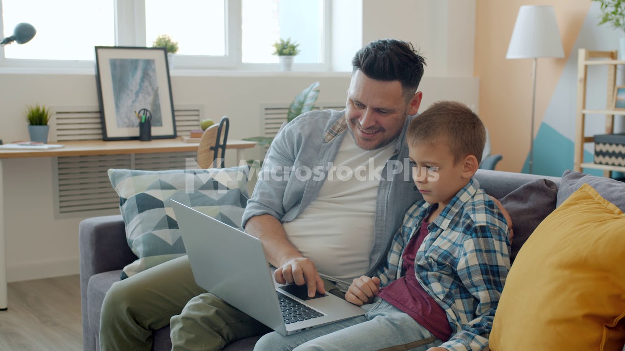 Father and child playing computer game using laptop in apartment having ...