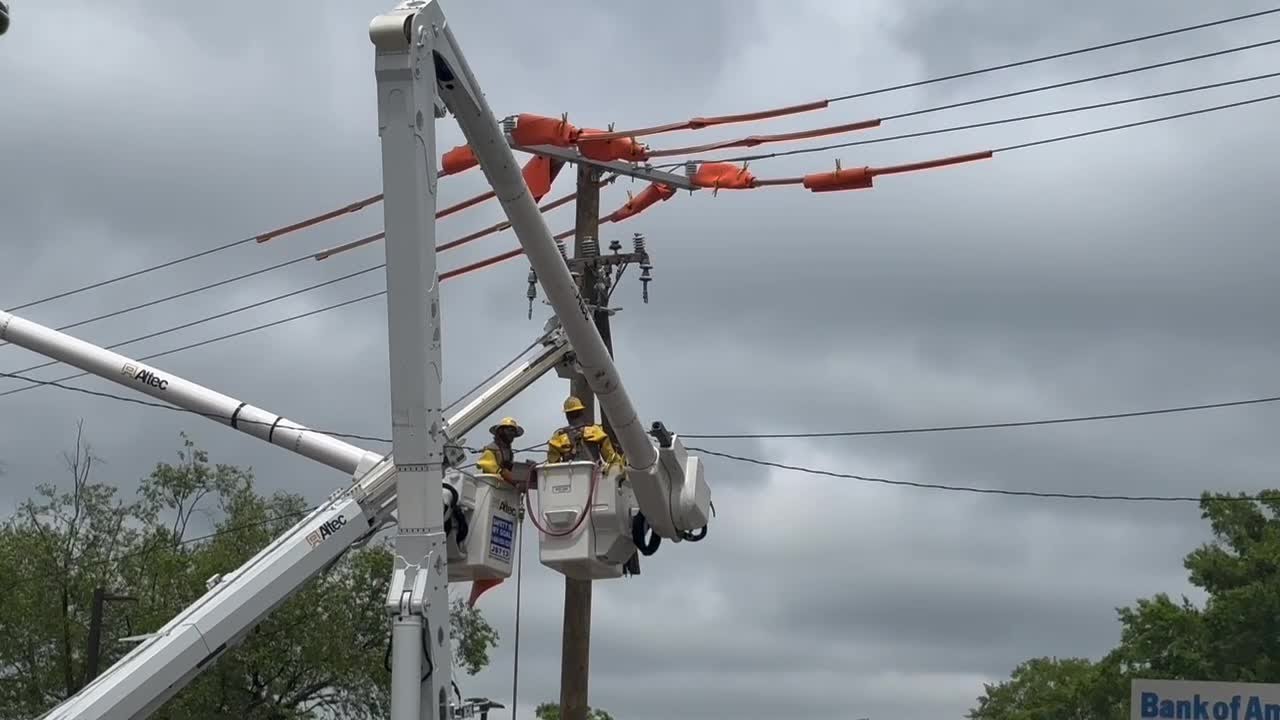 Utility crews work to repair broken power lines Sunday after a traffic ...