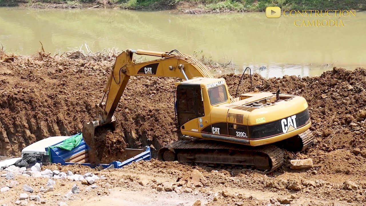 Excavator Working to Digging Dirt on to Dump Trucks in a deep River ...
