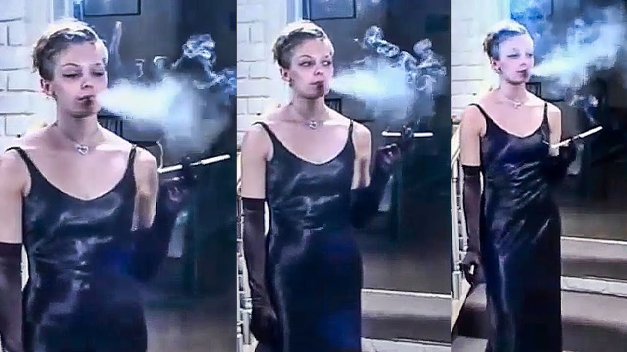Smoker girl smokes a cigarette with holder in sexy black silk satin ...