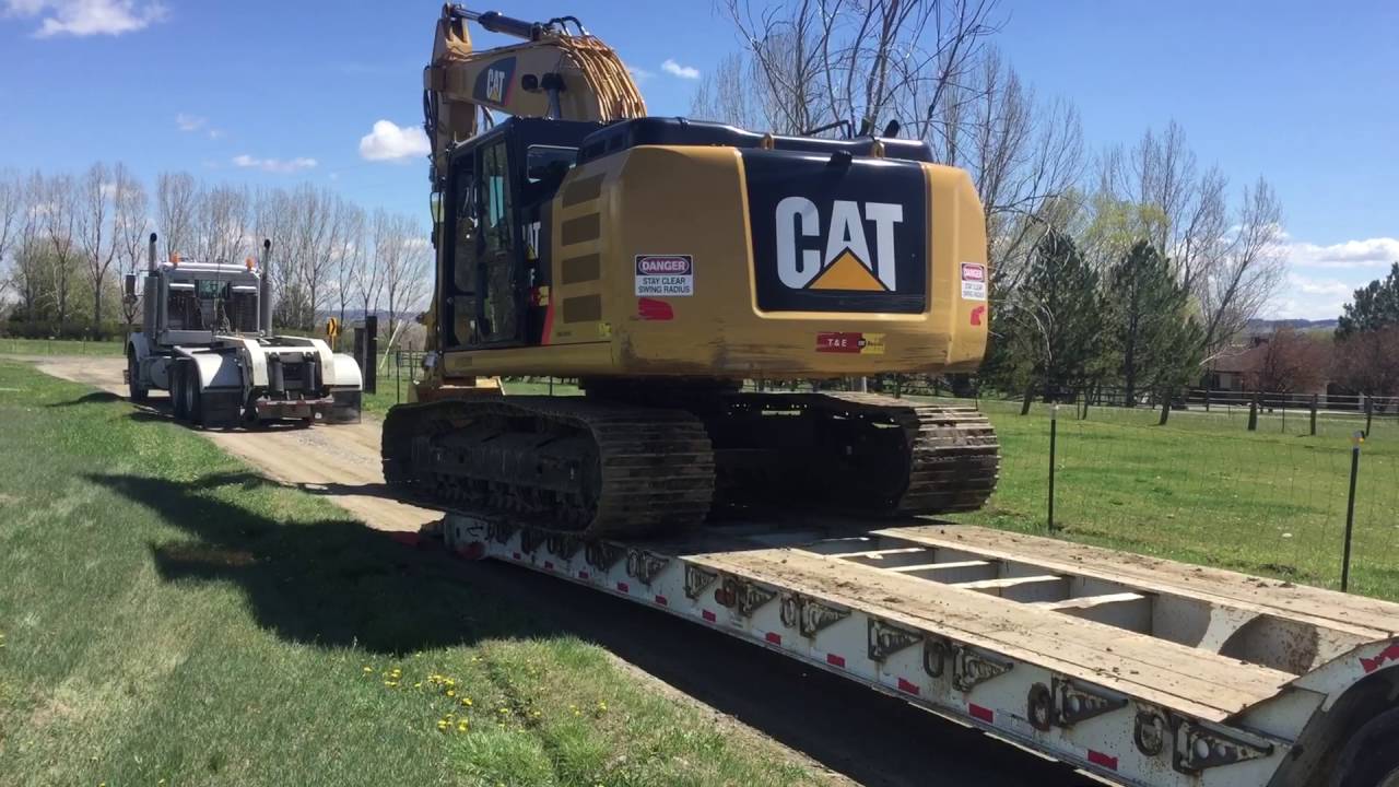 Unloading the cat 323f off the lowboy - YouTube