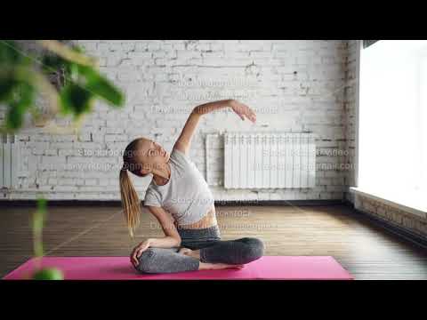 Attractive slim blonde is practicing yoga doing twist poses, bending to side then relaxing in lotus