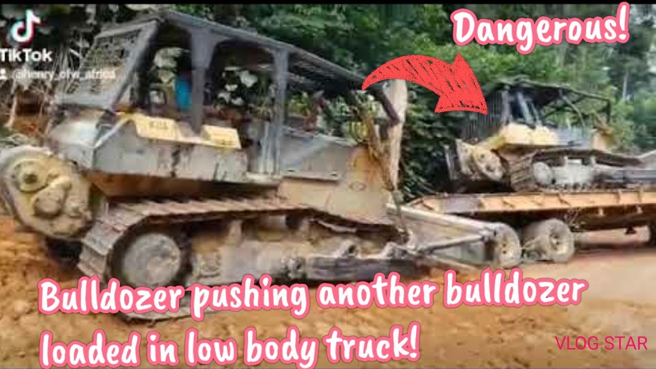 Dangerous job! Bulldozer pushing another dozer loaded in a low body ...