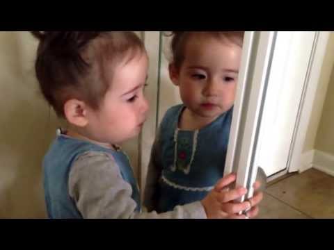 Toddler girl caught kissing self in mirror