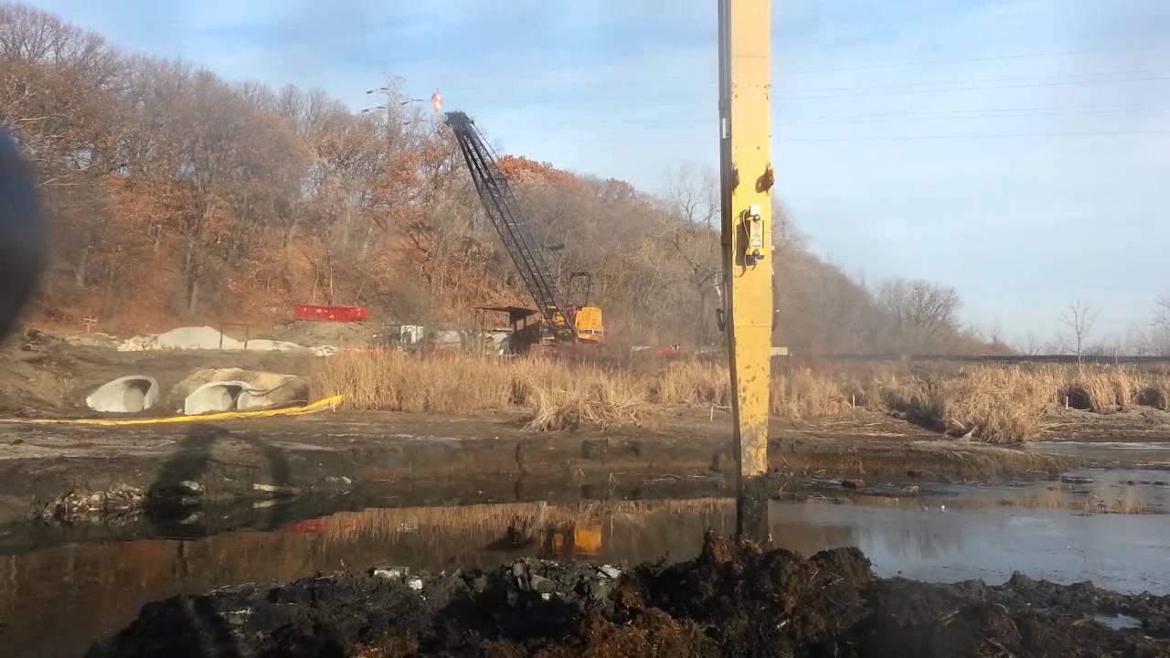 Long stick backhoe mucking out pond. - YouTube