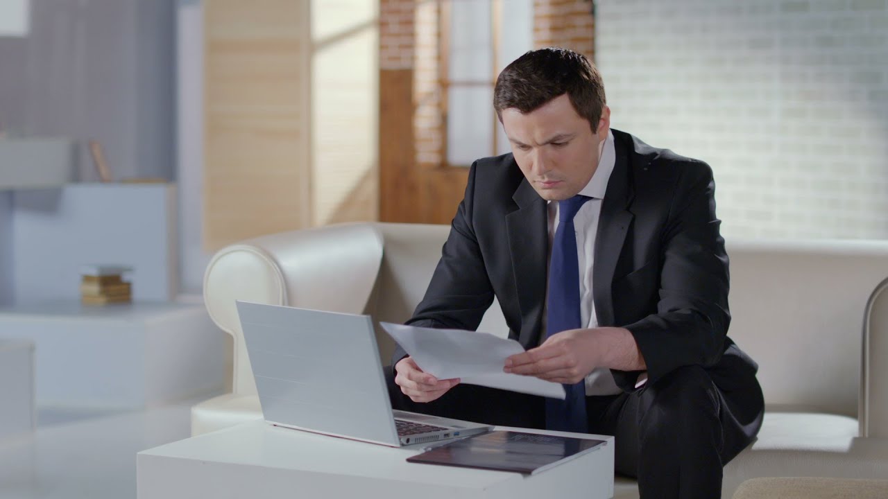 Businessman checking papers in office, web conference on laptop. Stock ...