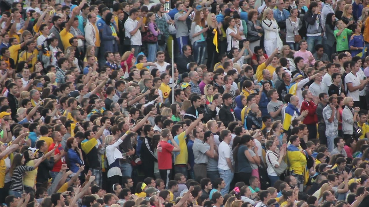 Crowd of people watching football. Lots of fans raise hands and shout ...