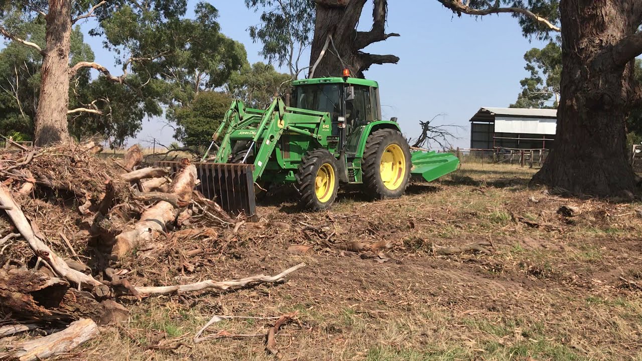 Clearing fallen timber with a tractor and stick rake front-end loader ...