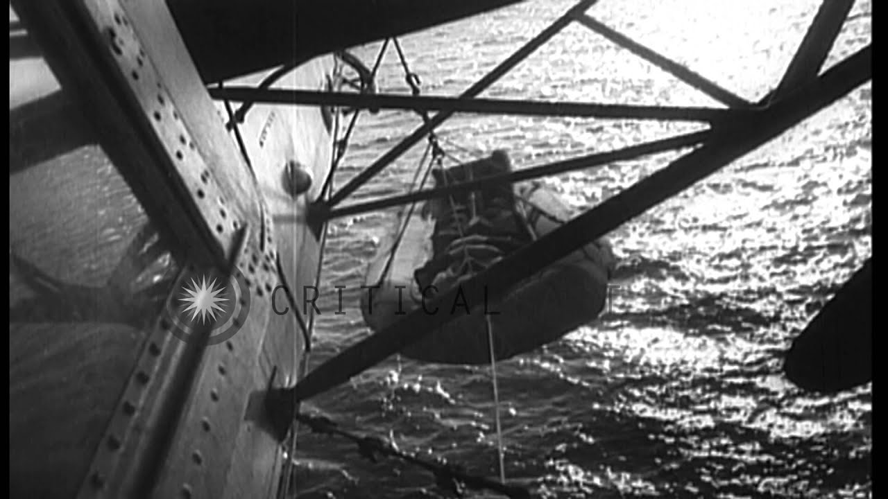 Blimp pulls up life raft and doctor climbs up ladder to airship to ...