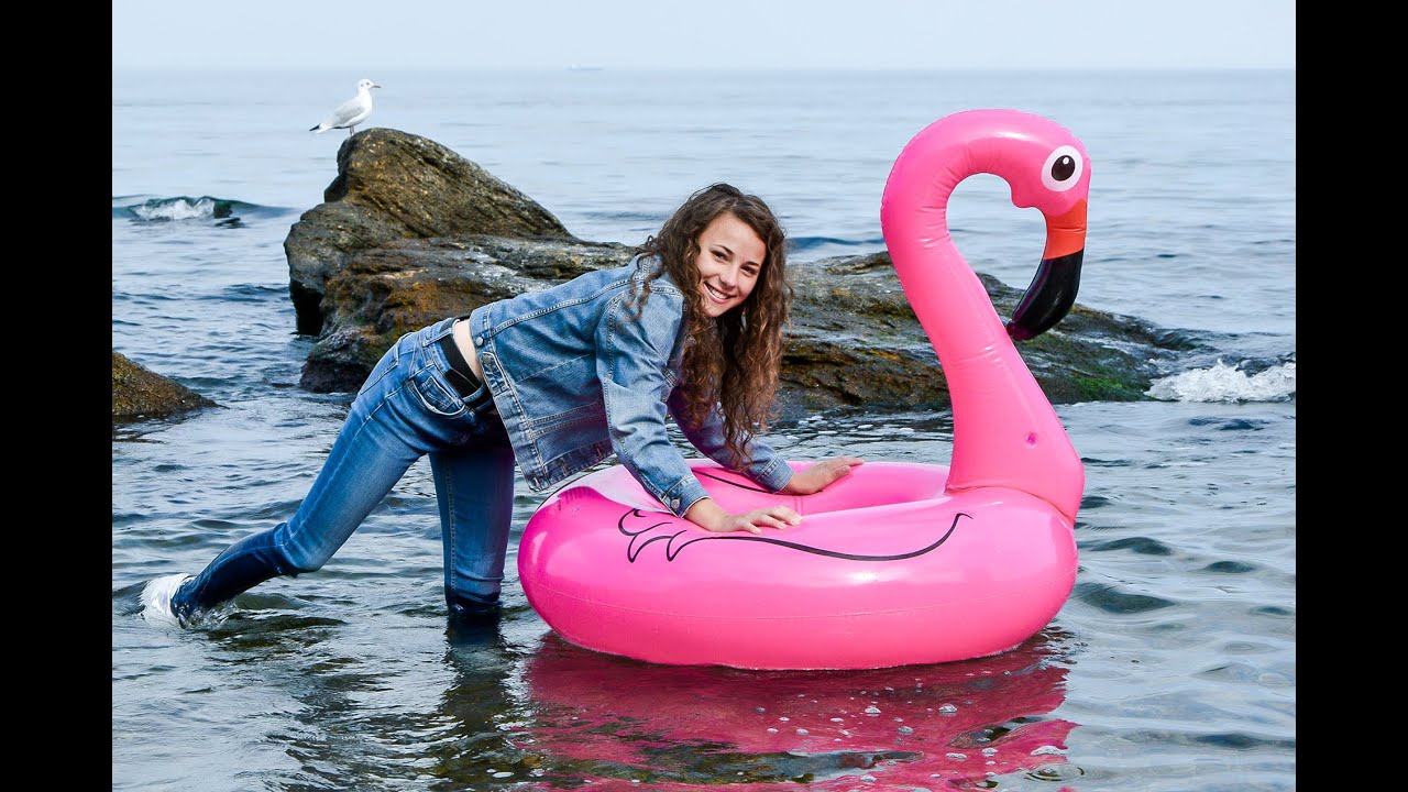 beautiful girl in wet jeans and a wet denim jacket on the beach posing ...