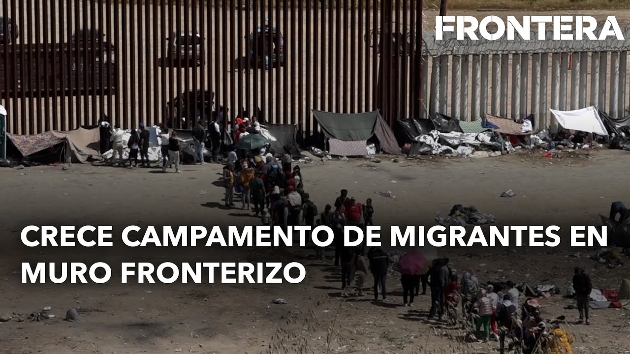 Crece campamento de migrantes en muro fronterizo - YouTube